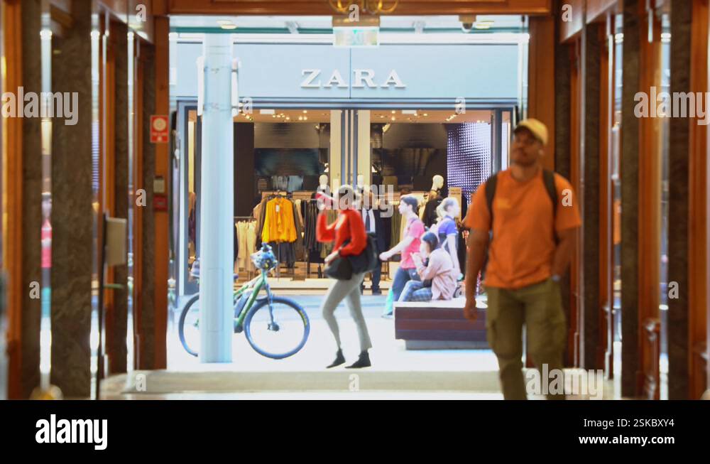 Dynamic zoom in shot capturing shoppers walking through fashion laneway ...