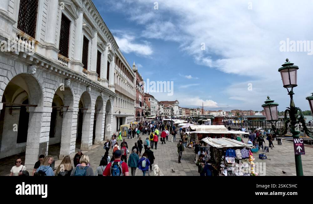 Tourists passing the Ponte della Paglia bridge and market in Venice ...