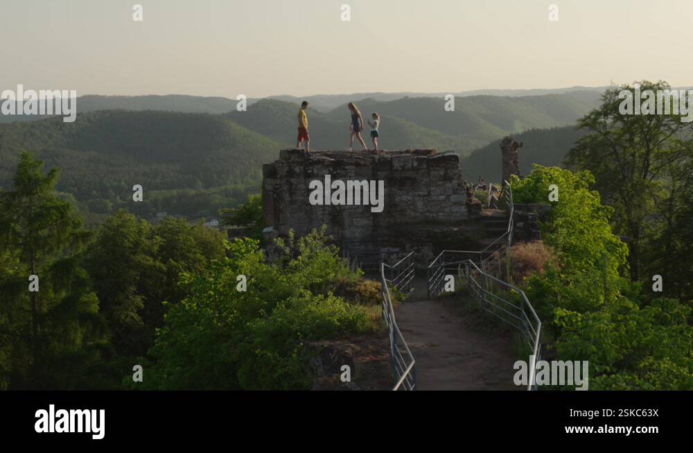 Family poses for photos on top of a rocky scenic lookout with mountains ...