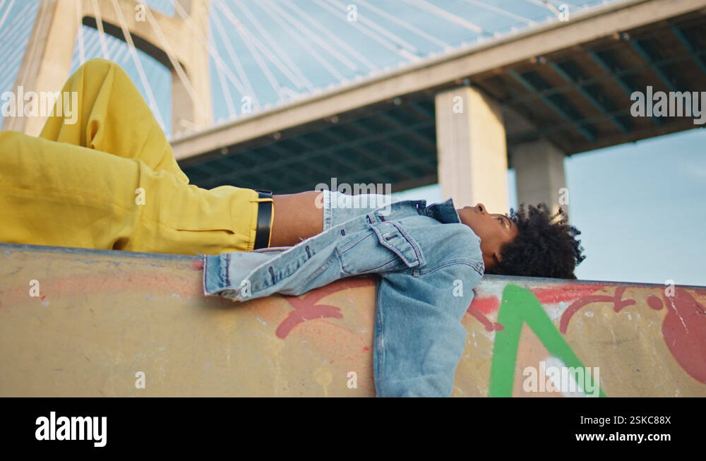 Black haired girl lying city street in front bridge close up. Woman ...