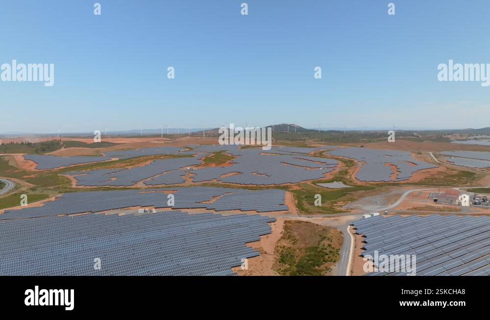 Drone dolly above solar farm fields and wind farms in the distance ...