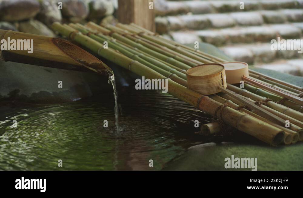 Water Flowing Out Of Bamboo Pipe Into Fountain With Pair Of Wooden ...