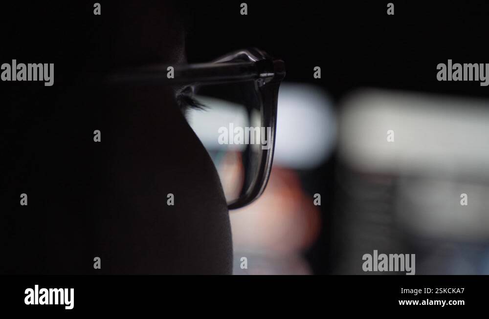 Rear view of closeup eyes wearing glasses with blurred monitor screen ...