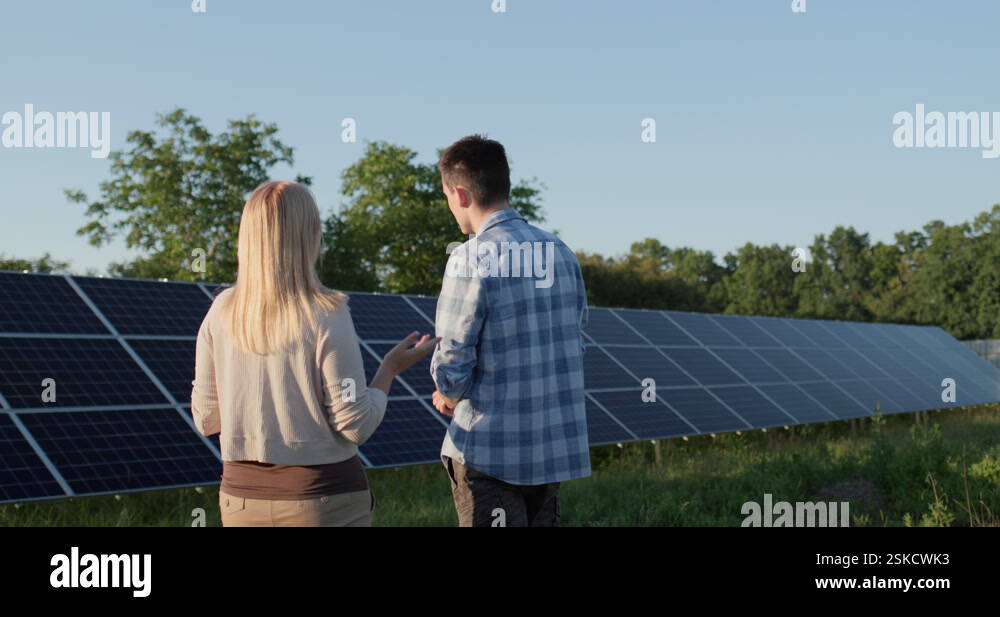 Two people are talking around solar panels at a small home solar power ...