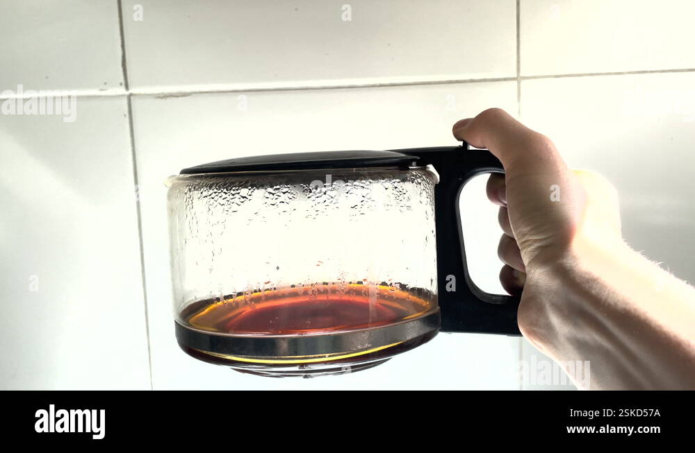 A hand holds a filter coffee pot, opening and closing its lid on a ...