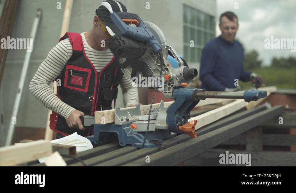 Builders sawing wood boards with circular saw machine on farm Stock ...