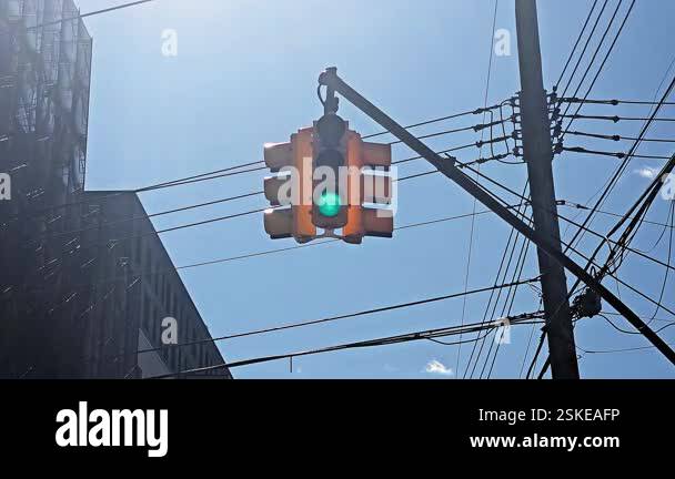 Traffic light with green signal hanging among cables on a bright sunny ...