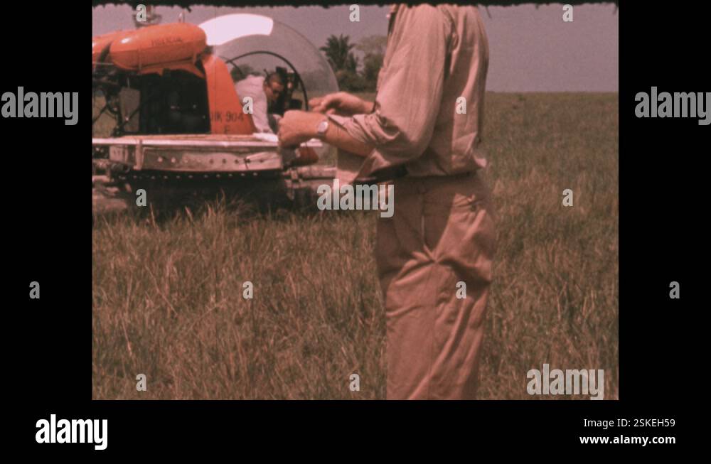 1960s: Wire turning on spool, tilt up to man with wire, helicopter ...