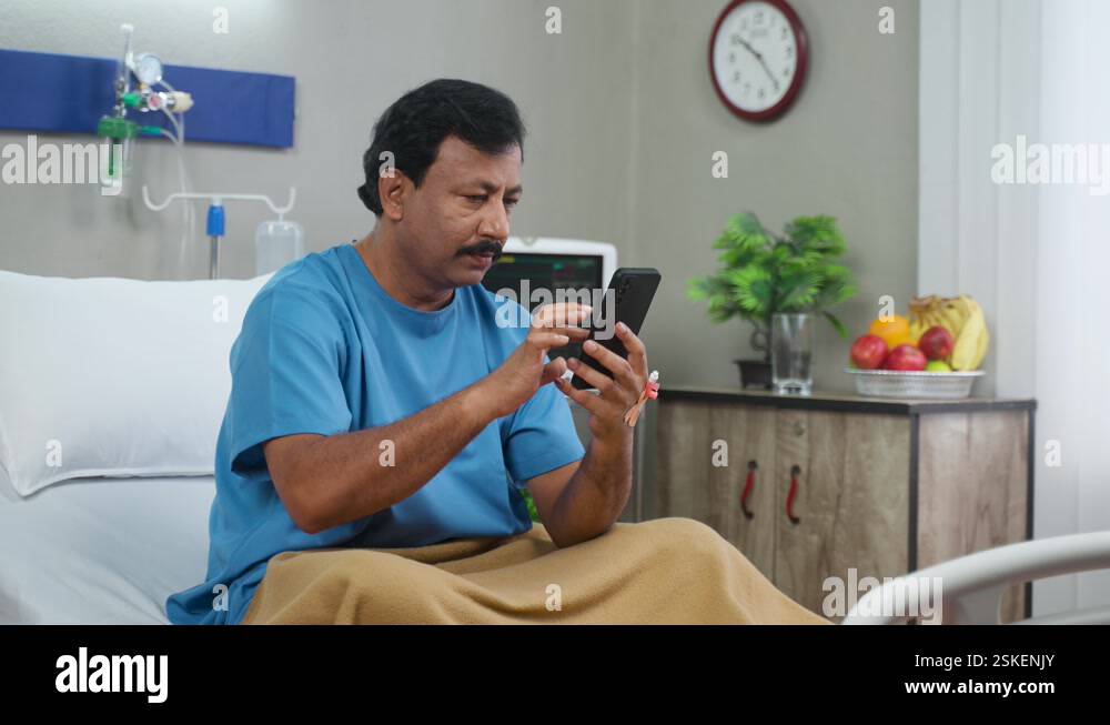 Indian admitted recovered patient using mobile phone on hospital bed ...