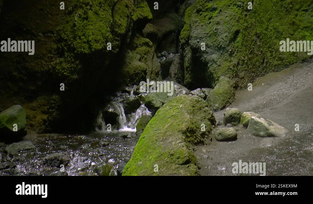Dark footage of small river stream and small waterfalls inside cave ...
