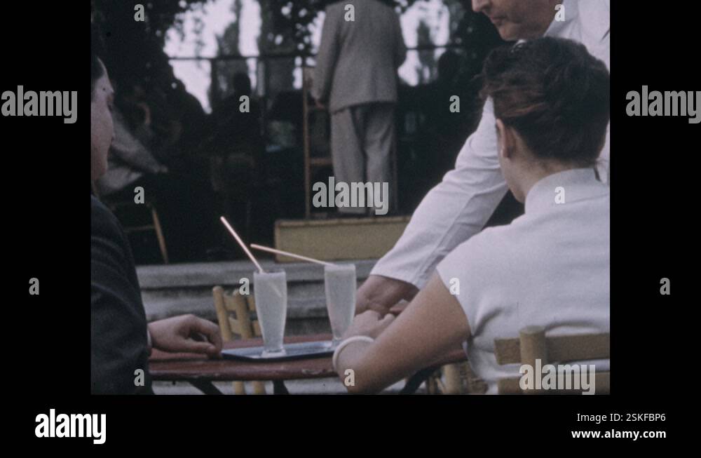 1960s: A man and woman sit at a table at an outdoor orchestra concert ...