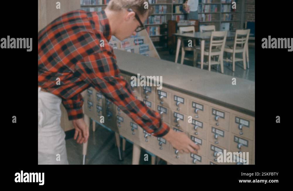 1960s: Man in library looks at Dewey decimal cards in drawer, puts ...