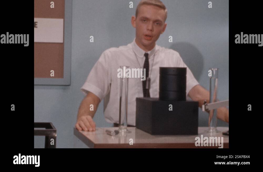 1960s: Man stands behind table with items on it, man talks. Man sets ...