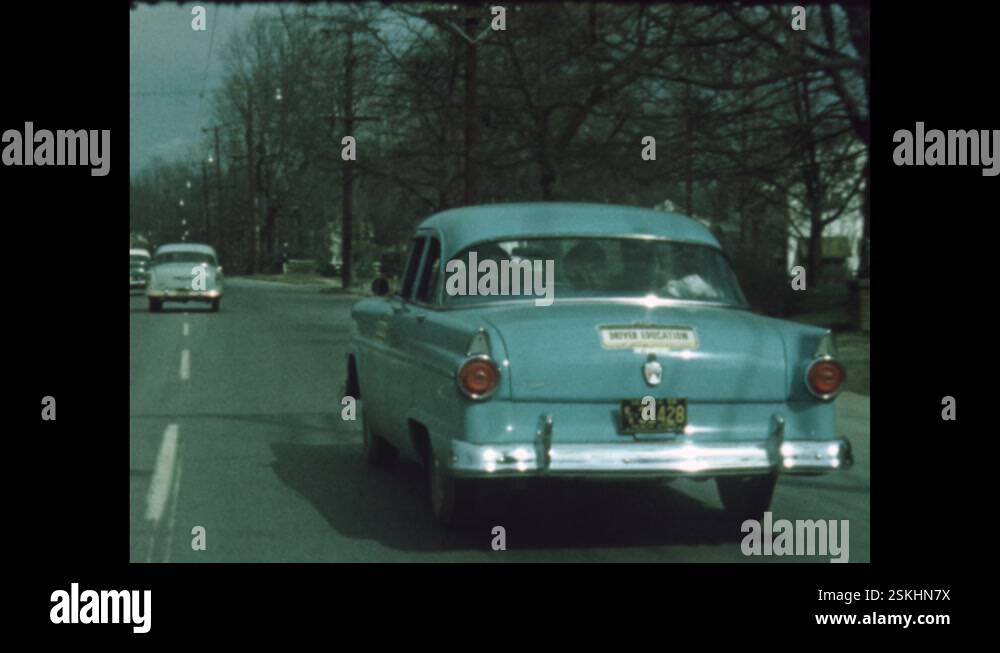 1960s: Cars drive down road. Woman sticks hand out window to signal ...