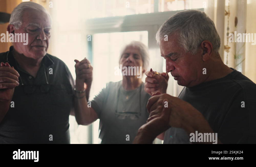 Devoted elderly people in unity at home while holding hands in PRAYER ...