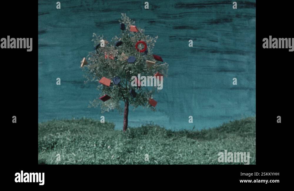 1970s: Boy looks up. Stop-motion animation: tree with different objects ...