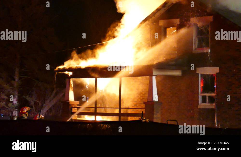 Fireman extinguish fire with the hose. Burning house fire during night ...