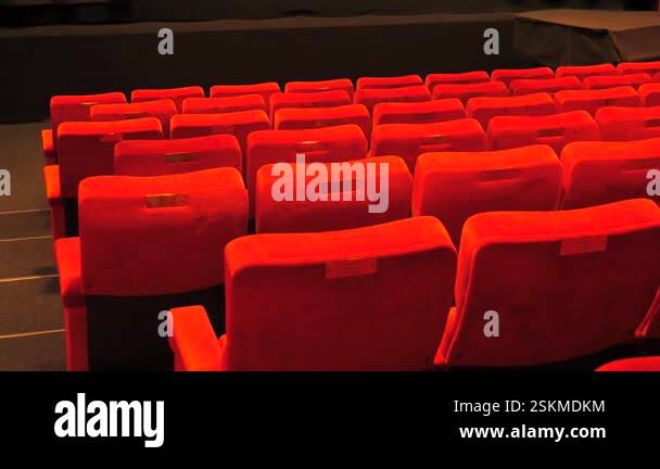 A striking view of plush red cinema seats arranged in perfect rows, creating an inviting yet ...