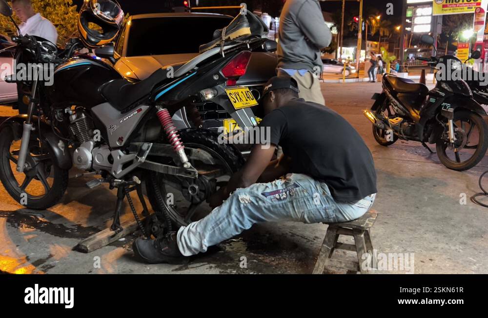 Young mechanic fixing a motorcycle wheel on a gas station Service man ...