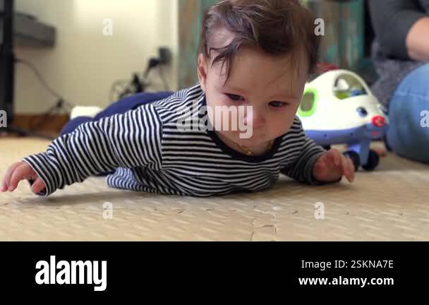 Baby lying on floor, propped on forearms, vomiting with visible spit-up ...