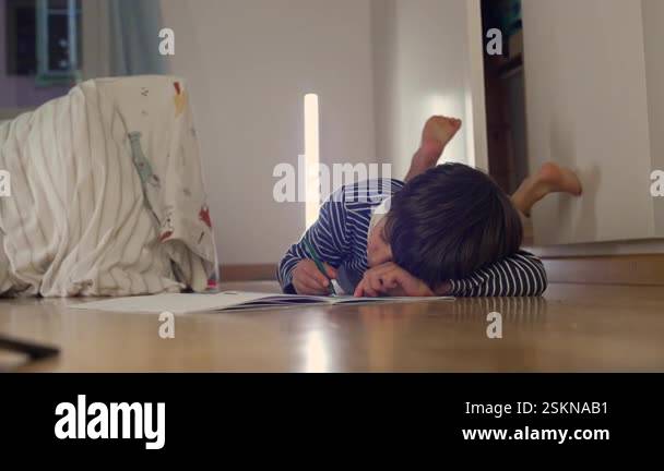 Young boy lying on the floor, resting his head on his arm while holding ... Young boy lying on the floor, resting his head on his arm while holding ...