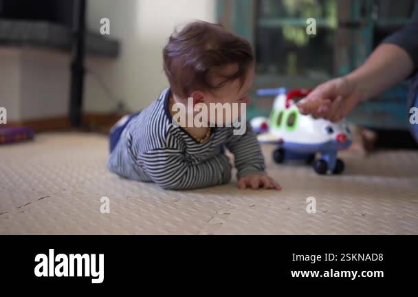 Baby lying on floor, lifting head and upper body while turning towards ...