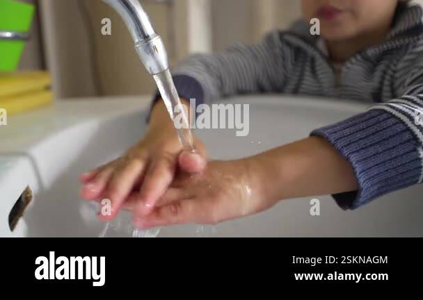 Child washing hands under running water in bathroom sink, close-up of ...