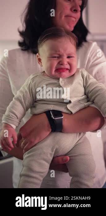 Mother holding crying baby, showing distress and discomfort, emotional ...