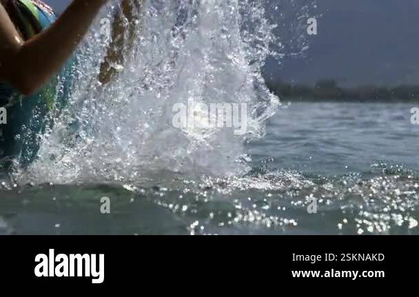 Partial view of little girl splashing water with hands in lake, high ...