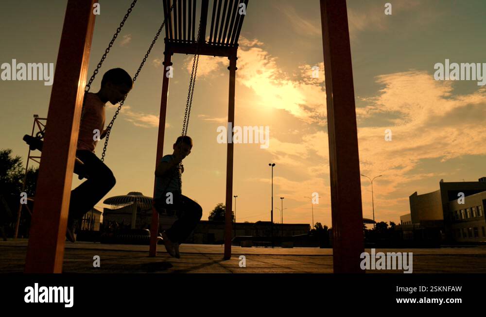 Boys swing on swings, friends play in childrens park. Silhouette of children Stock Video Footage ...