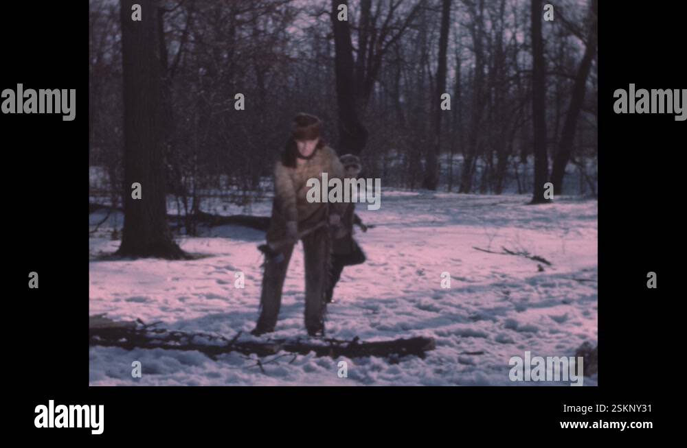 1950s: Man chops at a downed tree in a snowy woods. A boy points and ...