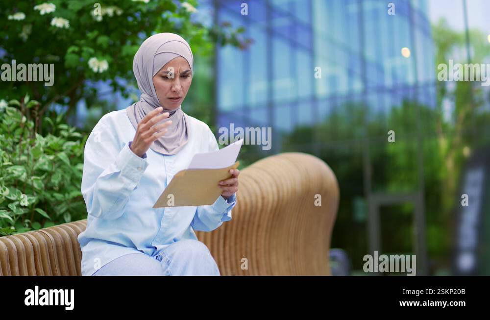 Disappointed young muslim female employee in hijab reading letter with ...