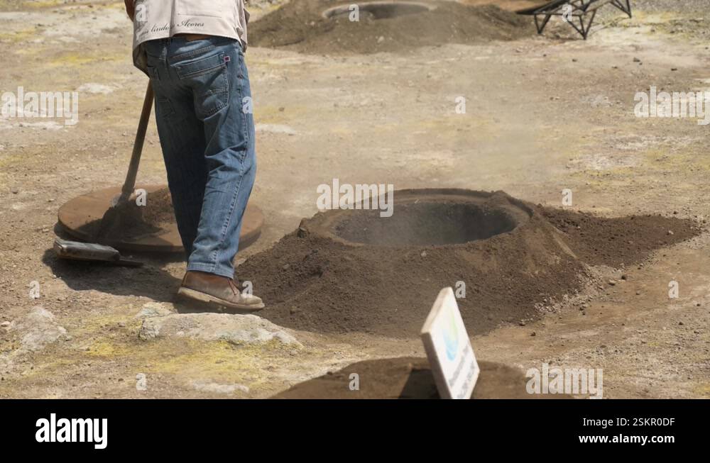 Worker removing the cover of the pit at the hot springs of lake Furnas ...