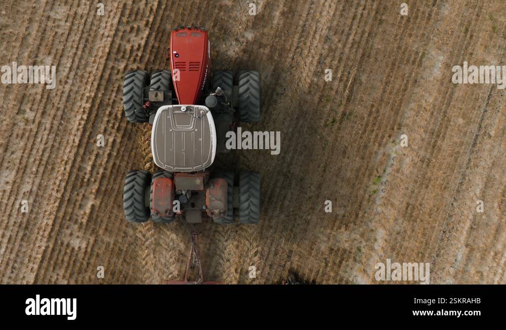 Disking the field. Big red Tractor cultivating land of Disc Harrow ...