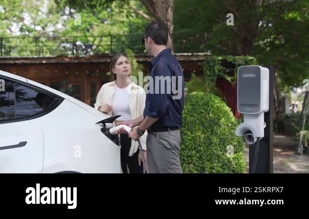 Slow motion couple recharge electric cars battery from charging station ...