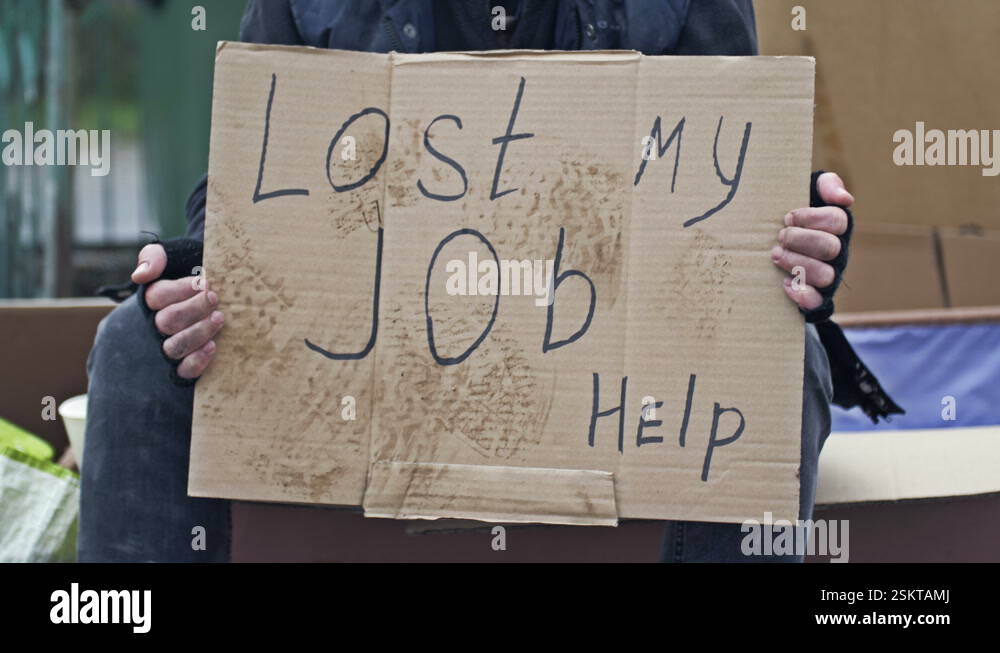 An untidy man is sitting with a cup of some drink and holding a ...