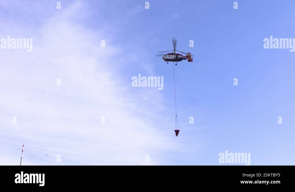 A Kamov Ka-32T firefighting helicopter flies in to fill the helibucket ...
