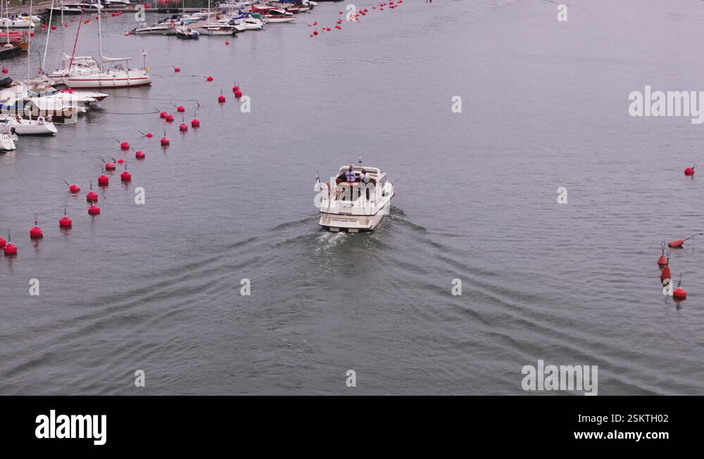 Back view of motorboat with Finnish flag sailing through port. Row of ...