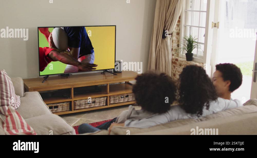 Biracial family watching tv with diverse male rugby players playing on screen Stock Video ...