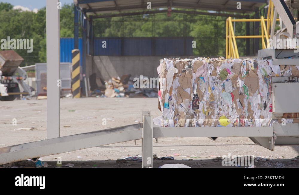 Truck drives by paper bale at recycling facility, wide static shot ...