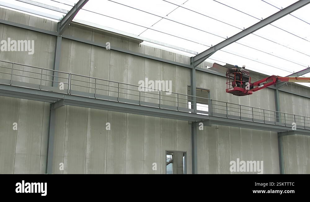 Industrial workers on a scaffold in assembly of metal structure of a ...