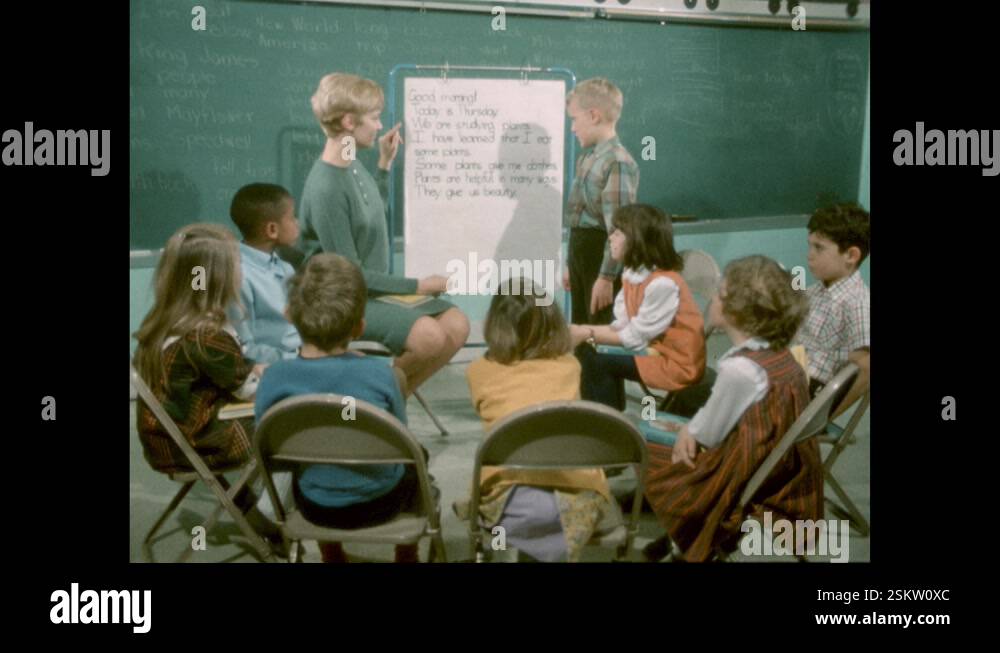 1960s: film slate, boy in classroom stands and reads from poster as ...