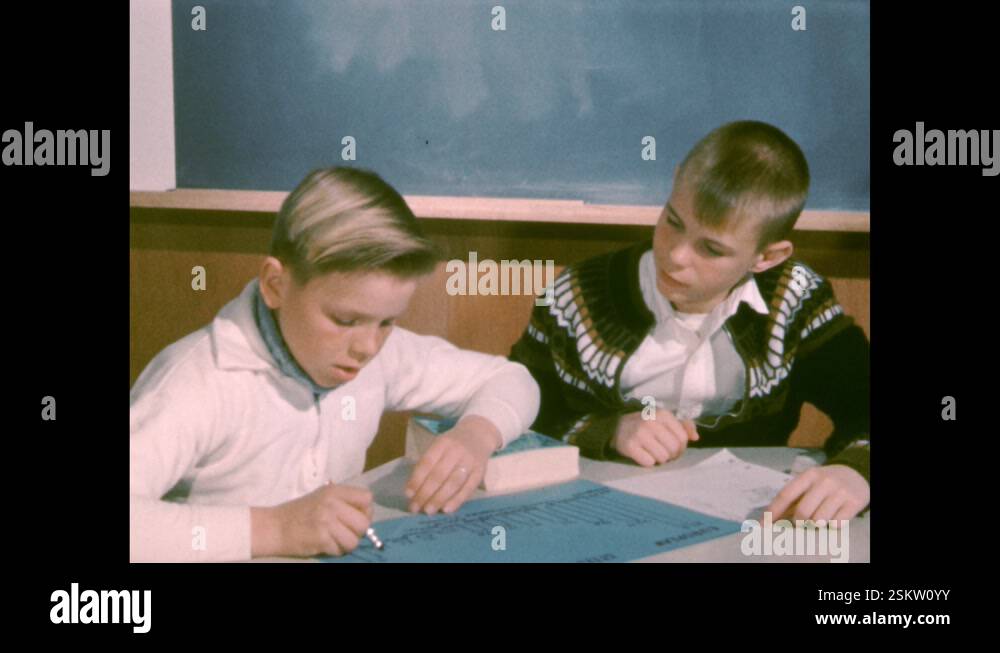 1960s: Two boys study in classroom. Boy finishes chart and other boy ...