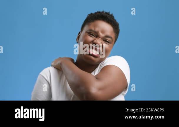 A young African American woman displays discomfort, gripping her ...