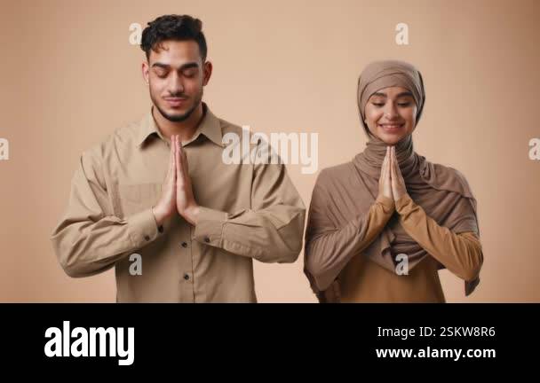 A married Arab couple stands together in a studio with a neutral ...