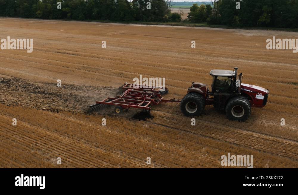 Big red Tractor Pulling Disc Harrow Through Field in Preparation soil ...