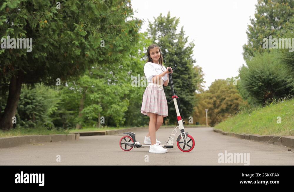 A little girl is learning to ride an electric scooter. Riding a scooter ...