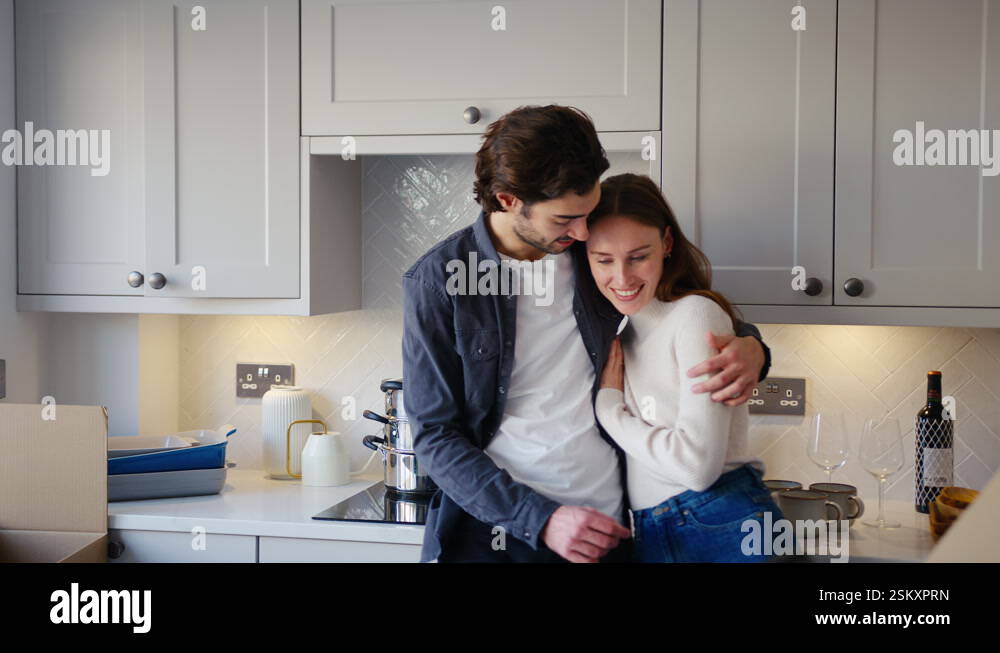 Loving Couple Hugging In Kitchen Of New Home As They Unpack Boxes On Moving In Stock Video ...
