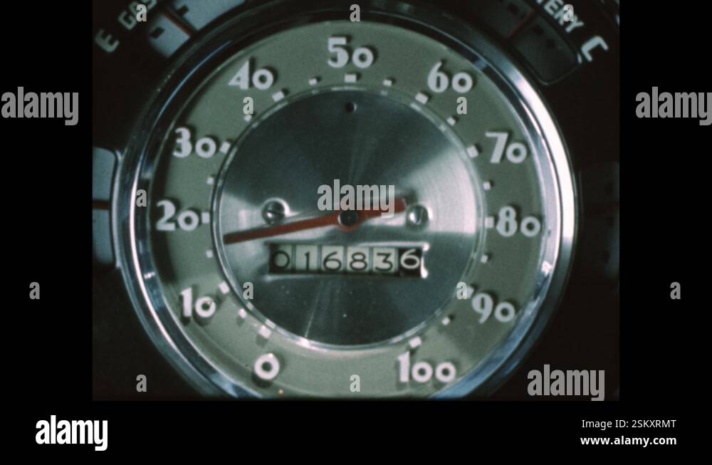 1950s: Car. Speedometer. Hand holds shooting slate. Man rides in car ...