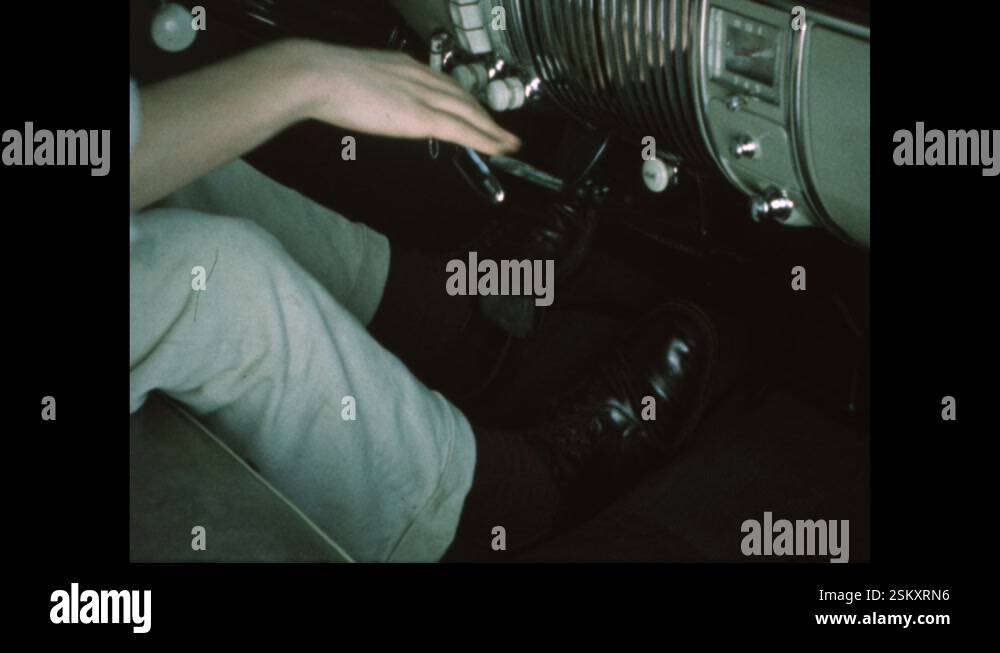 1950s: Man starts car. Hand holds shooting slate. Foot presses pedals ...